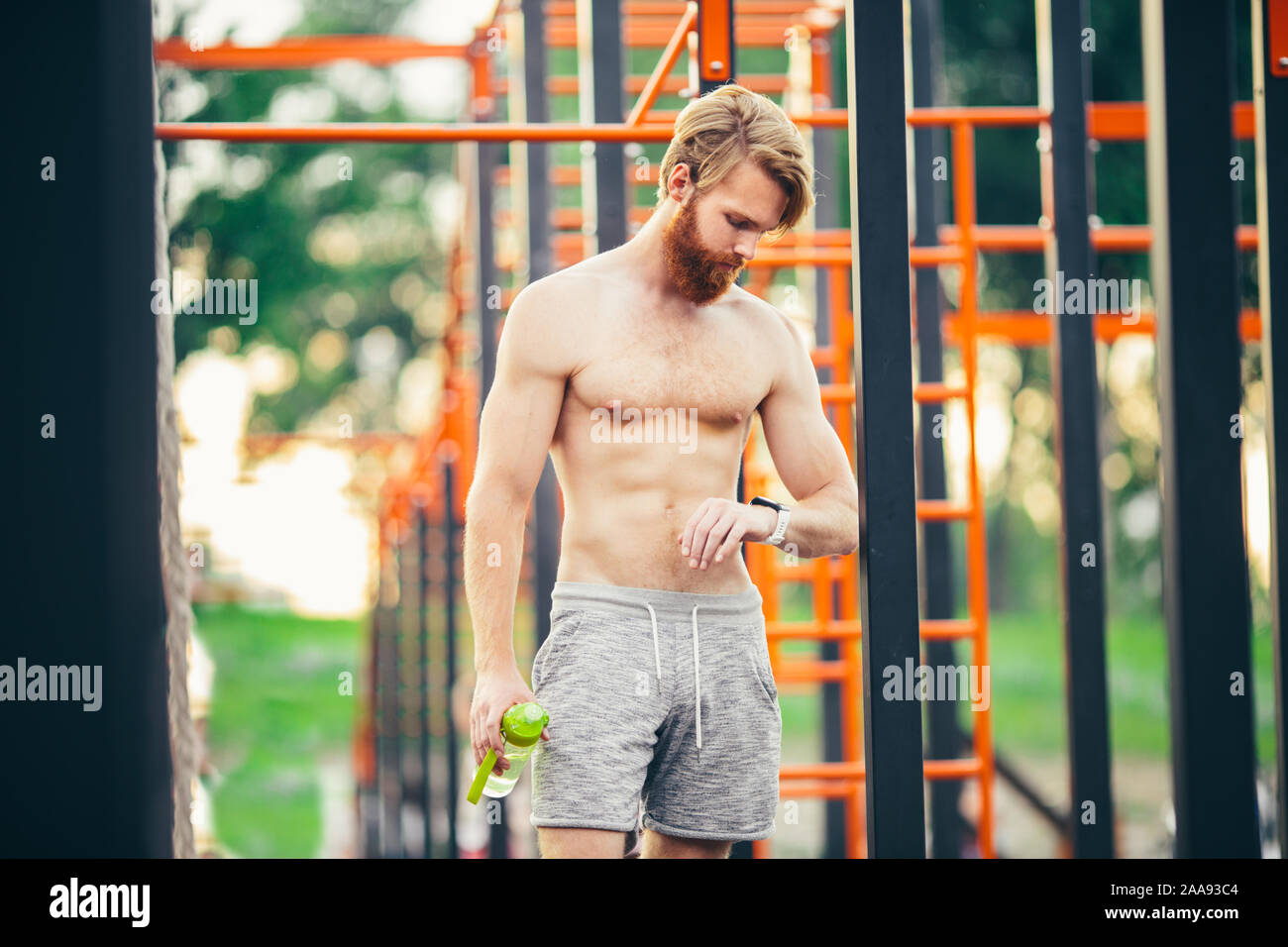 Sports man looking the watch standing treet gym. Young Muscular athlete ...