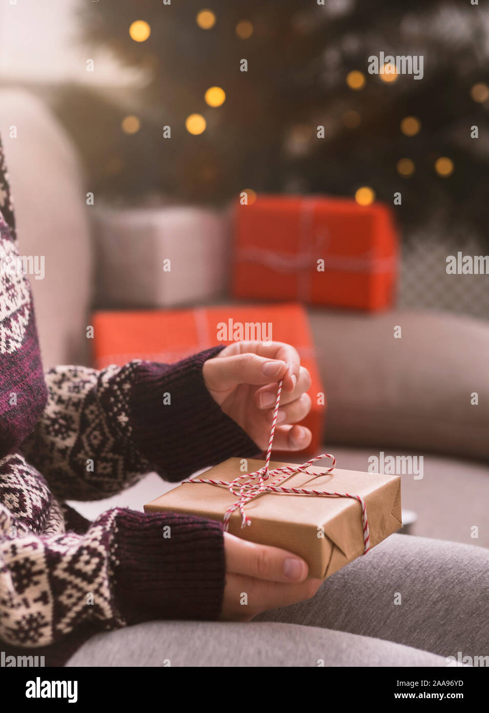 Woman unpacking Christmas gift over background with tree Stock Photo ...