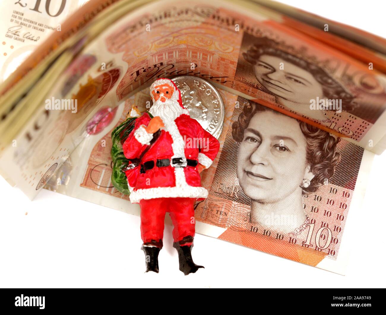 A santa claus figurine standing in front of some new ten pound notes ...