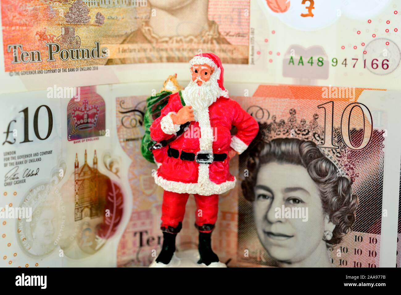 A santa claus figurine standing in front of some new ten pound notes ...