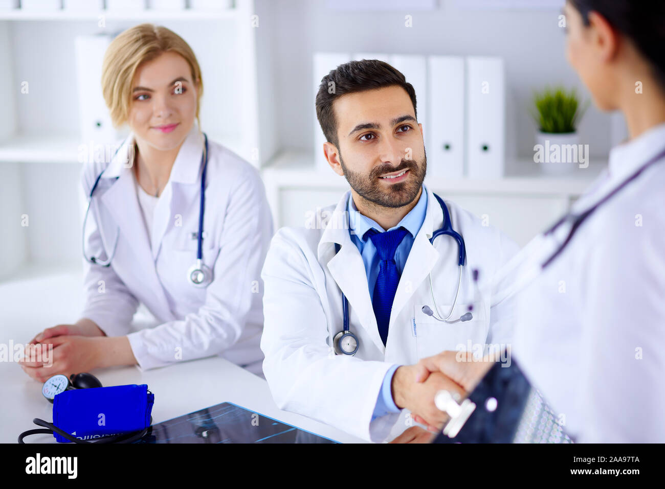 Young arab doctor shakes hands with nurses in a hospital. Group of ...