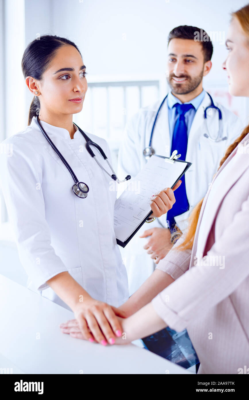 Young arab doctor explains diagnosis to patient in office and holds ...