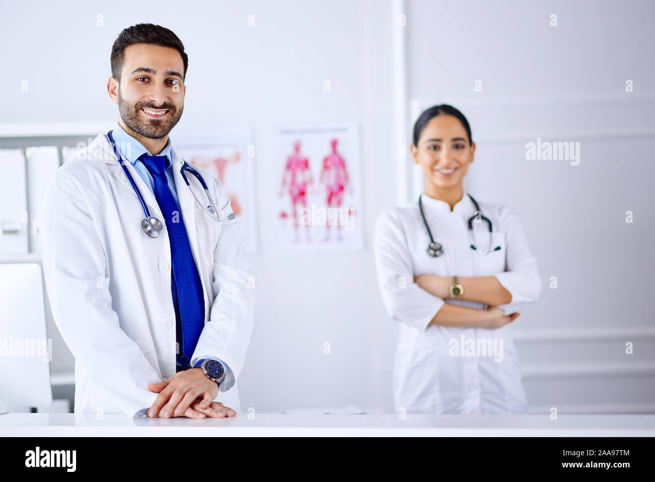 Two young smiling arab doctors standing in consultation room in ...