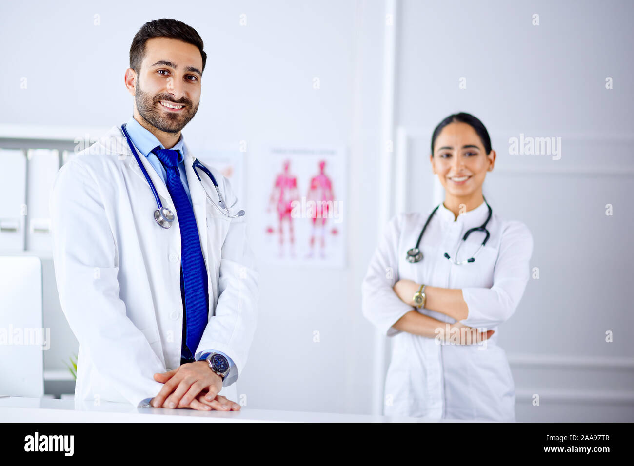 Two young smiling arab doctors standing in consultation room in ...