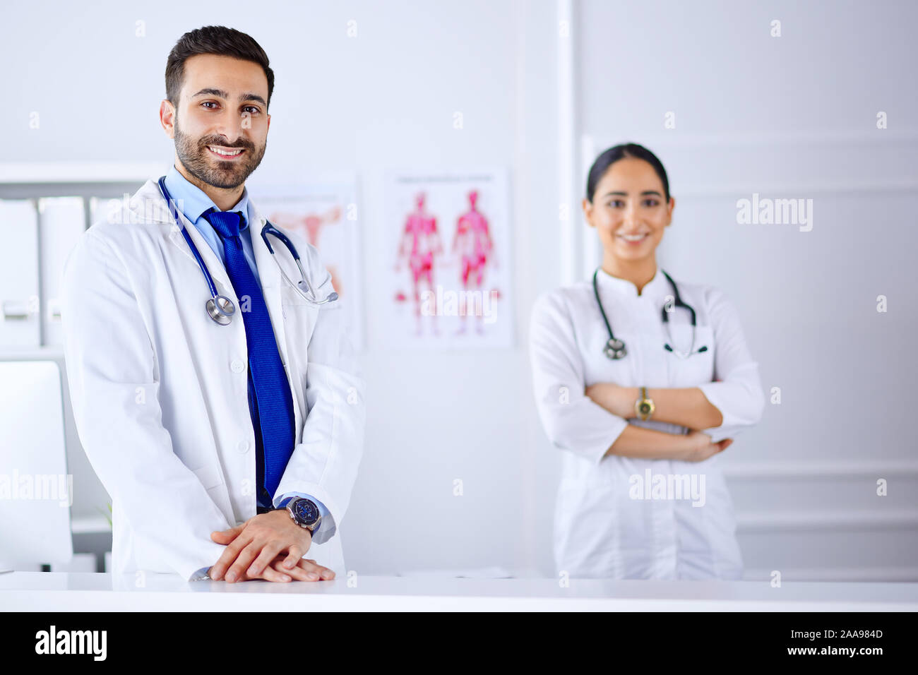 Two young smiling arab doctors standing in consultation room in ...