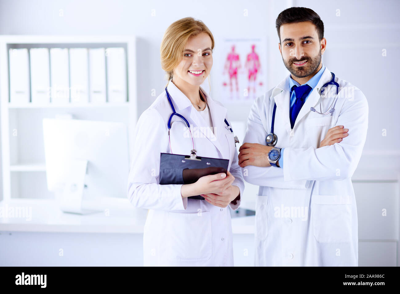 Two doctors all standing together in a consultancy room and holding ...