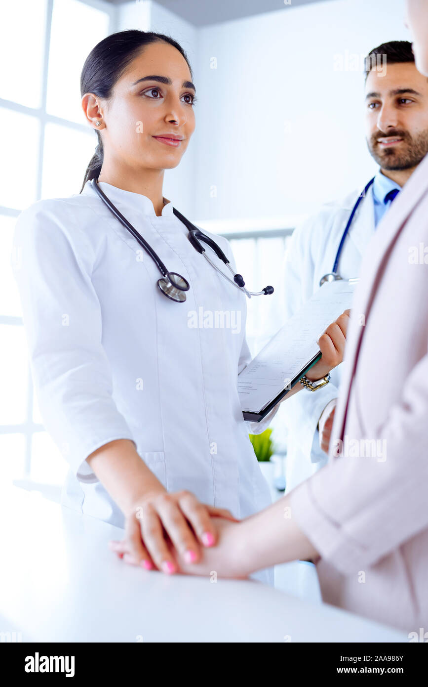 Young arab doctor explains diagnosis to patient in office and holds ...