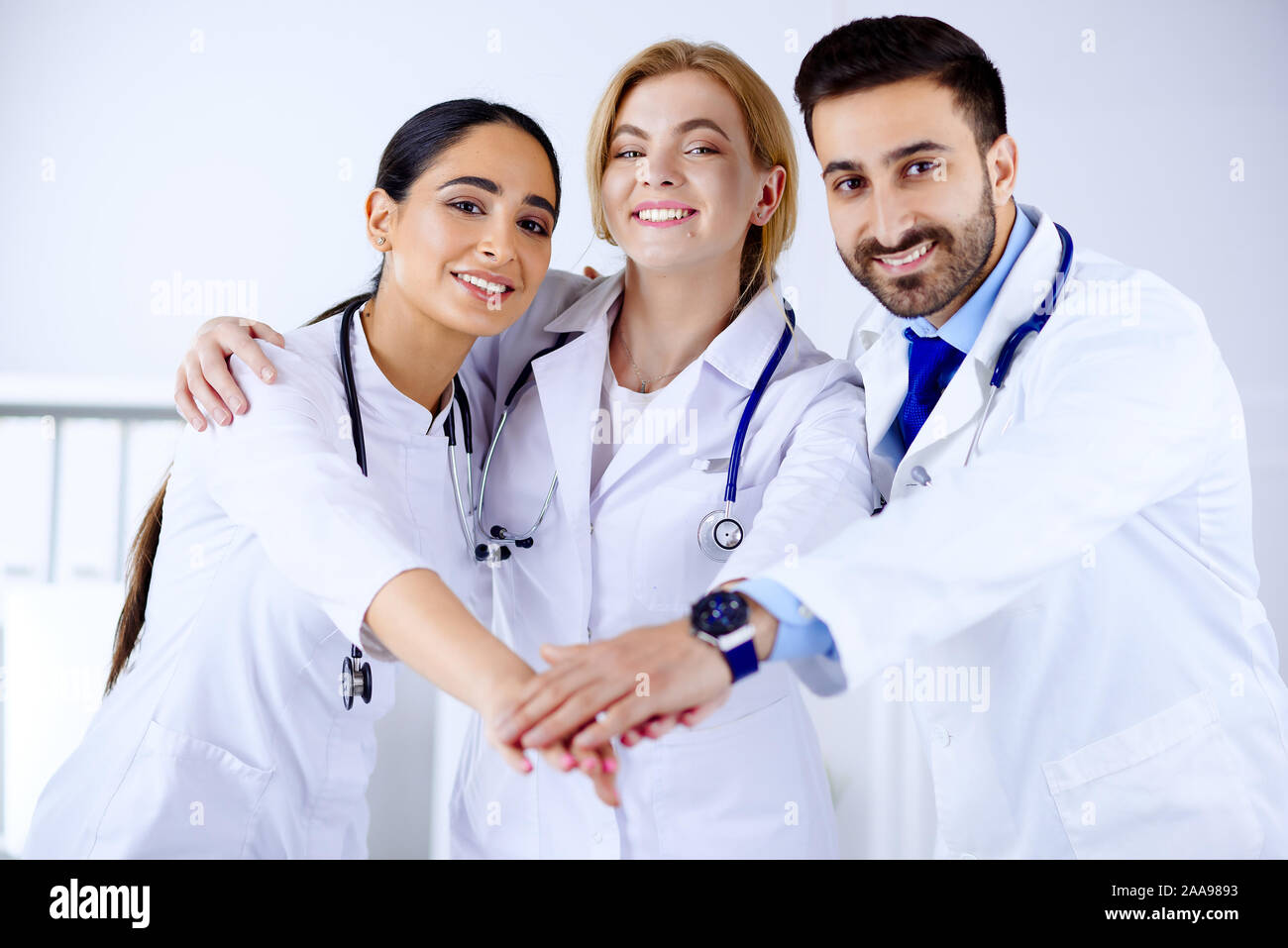 Group of doctors standing in office stacking hands together Stock Photo ...