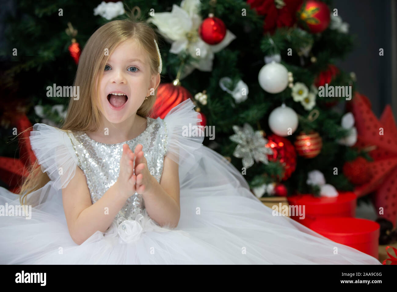 Beautiful child with a christmas gift. Dressing up girl at the New Year ...
