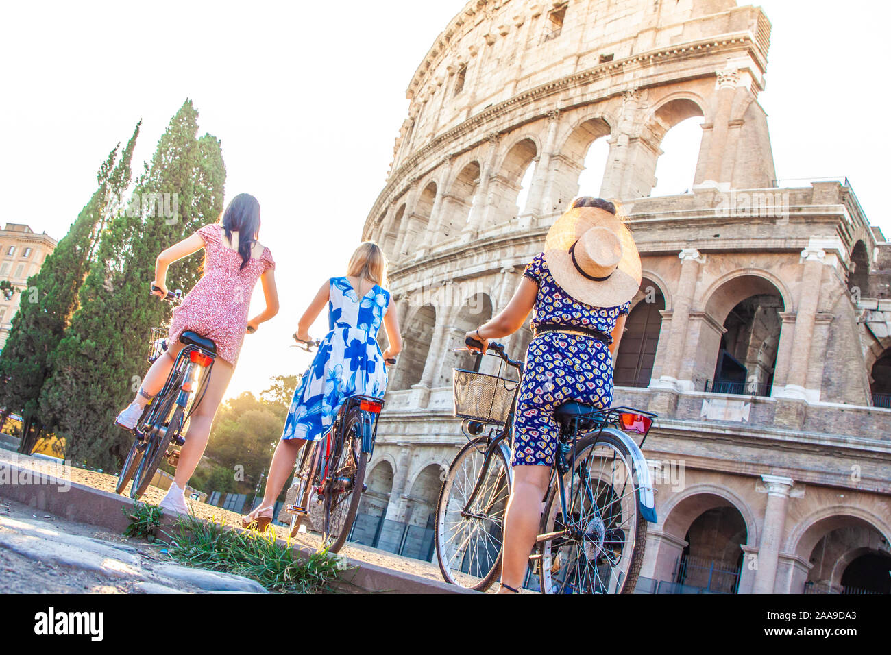 Three happy young women friends tourists with bikes at Colosseum in ...