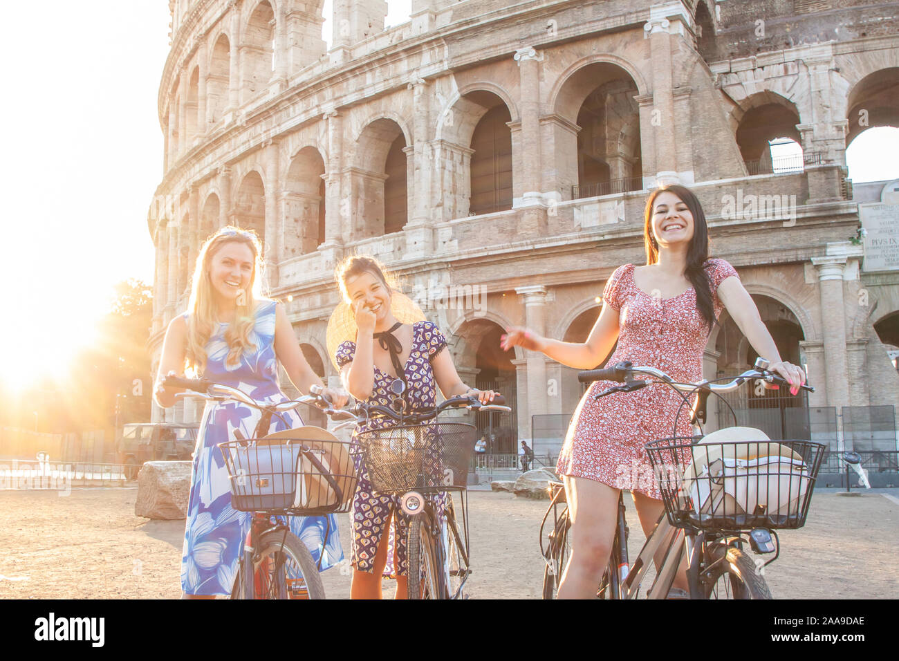 Three happy young women friends tourists with bikes at Colosseum in ...