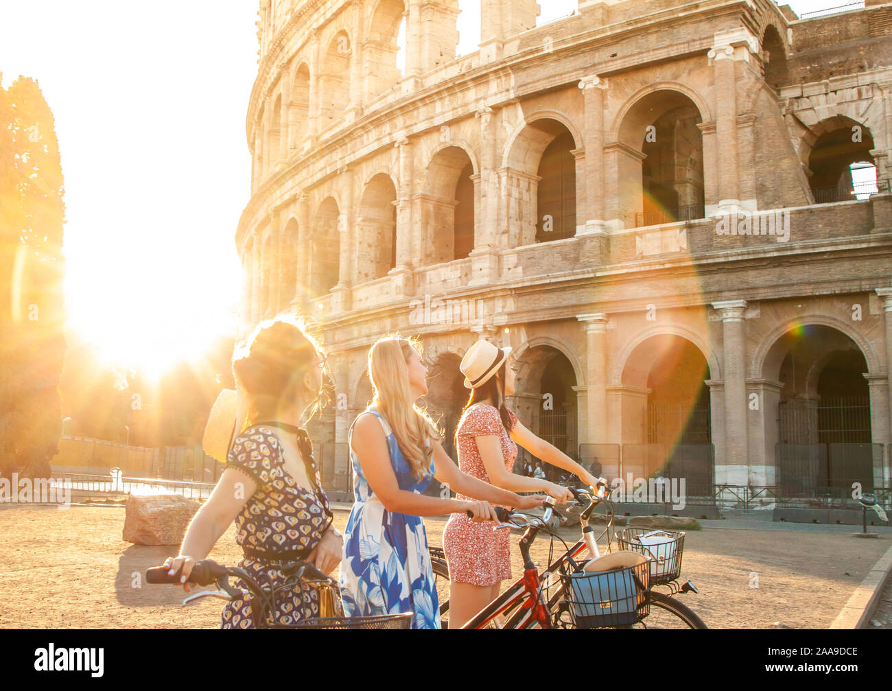Three happy young women friends tourists with bikes at Colosseum in ...