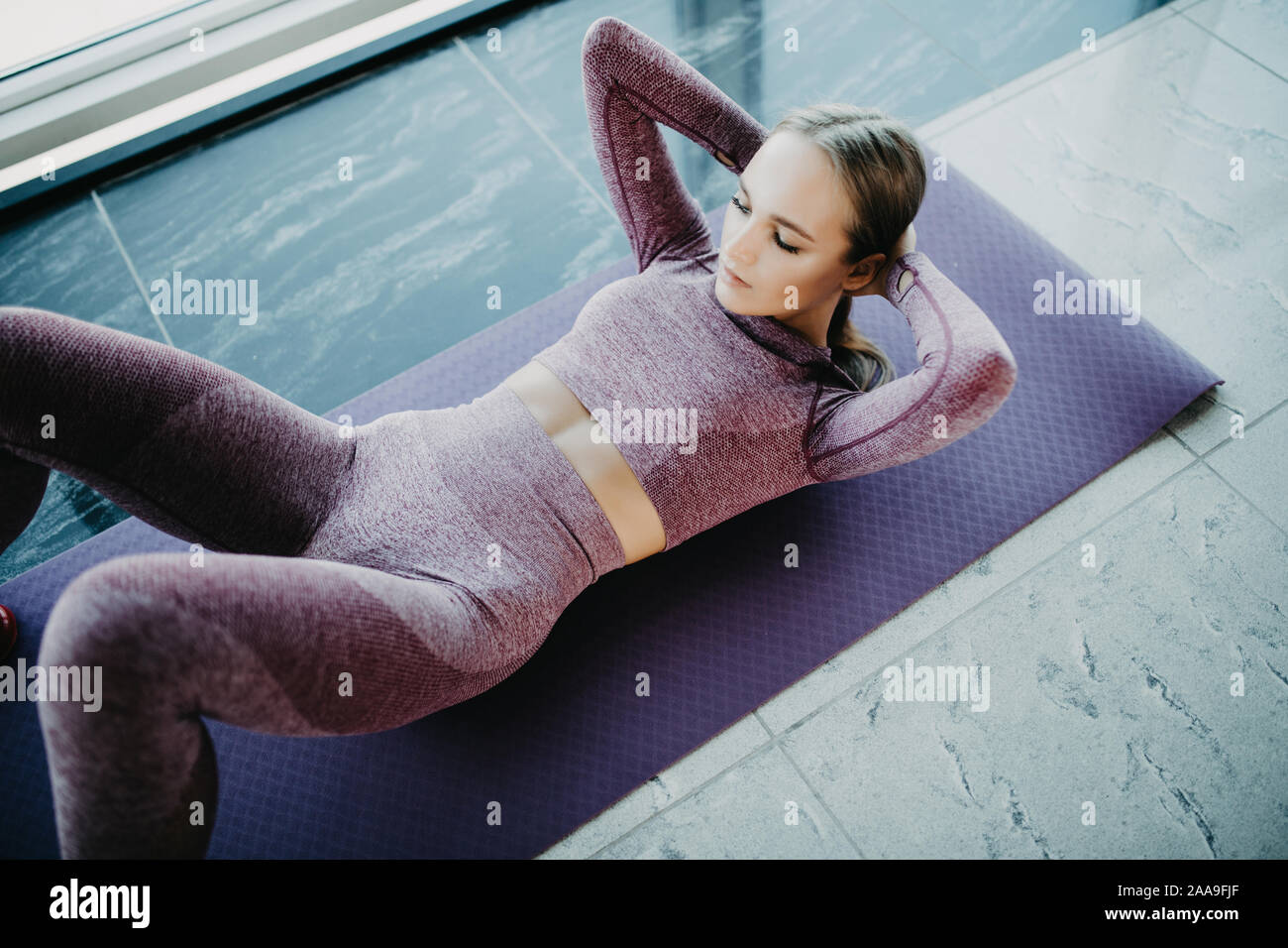 Sporty young female athlete on yoga mat doing situps in gym. Fitness ...