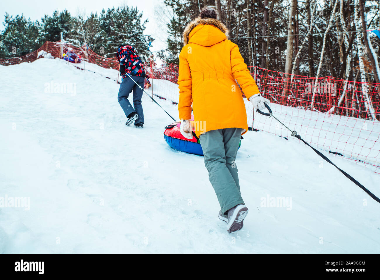 people climbing up by hill for snow tubing Stock Photo - Alamy
