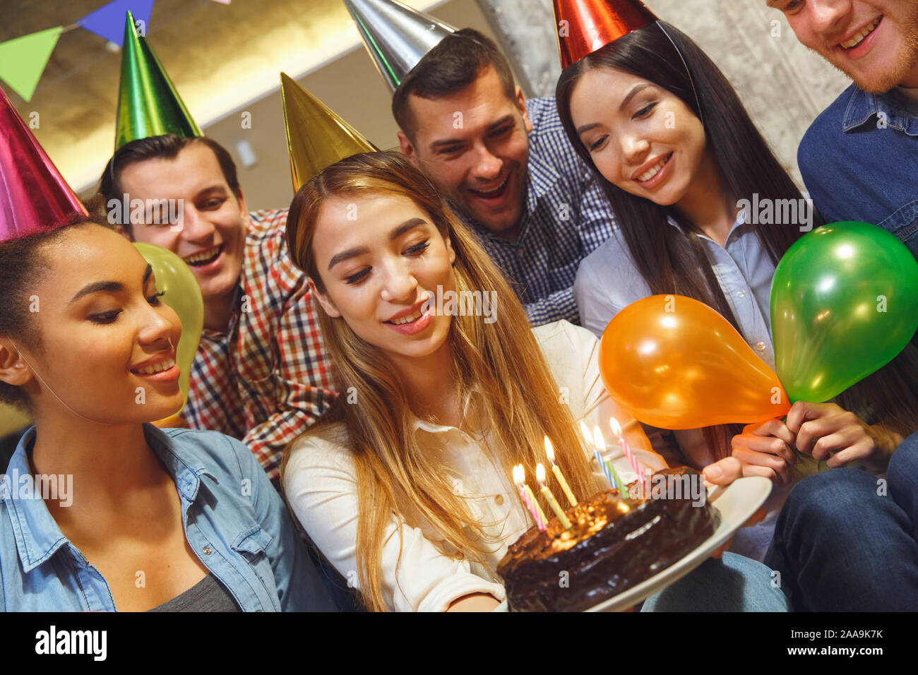 Group of friends having party indoors fun together girl making wish ...