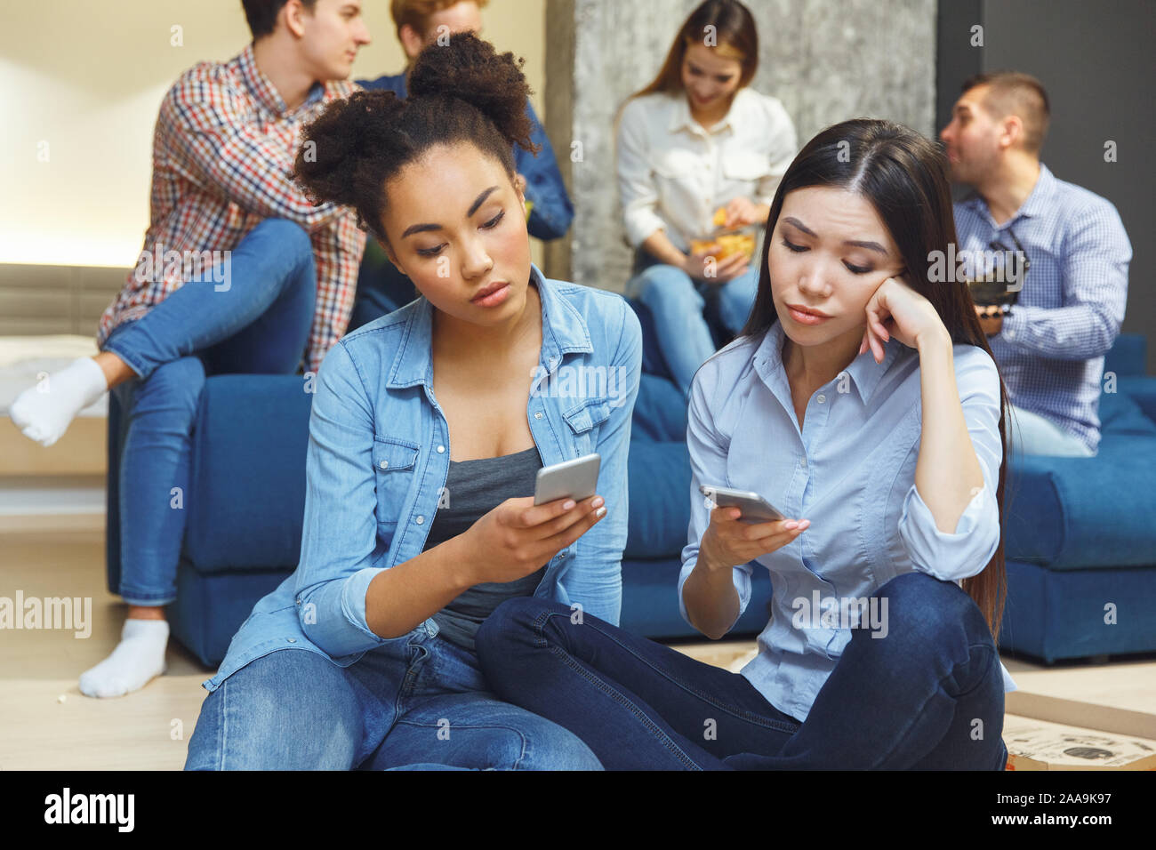 Group of friends having party indoors fun together two girls sitting ...