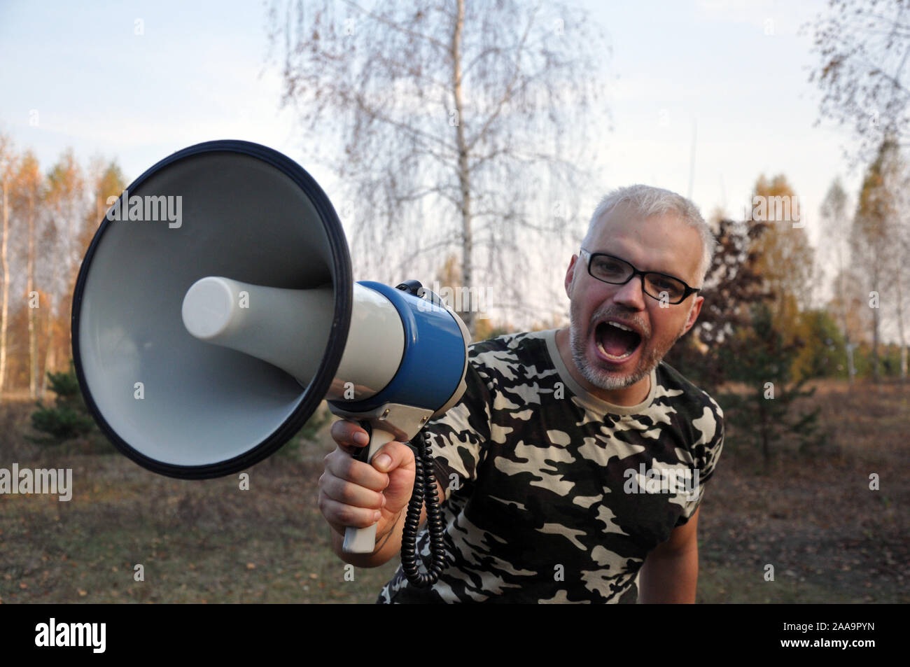 Closeup portrait of a young man screaming into a megaphone. Shout ...