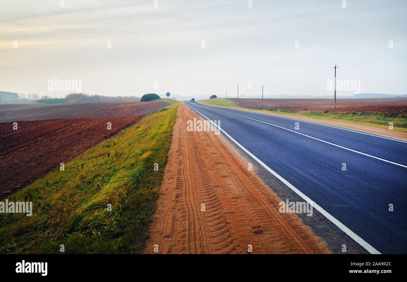 Asphalt road in the countryside, sandy roadside and plowed field Stock ...