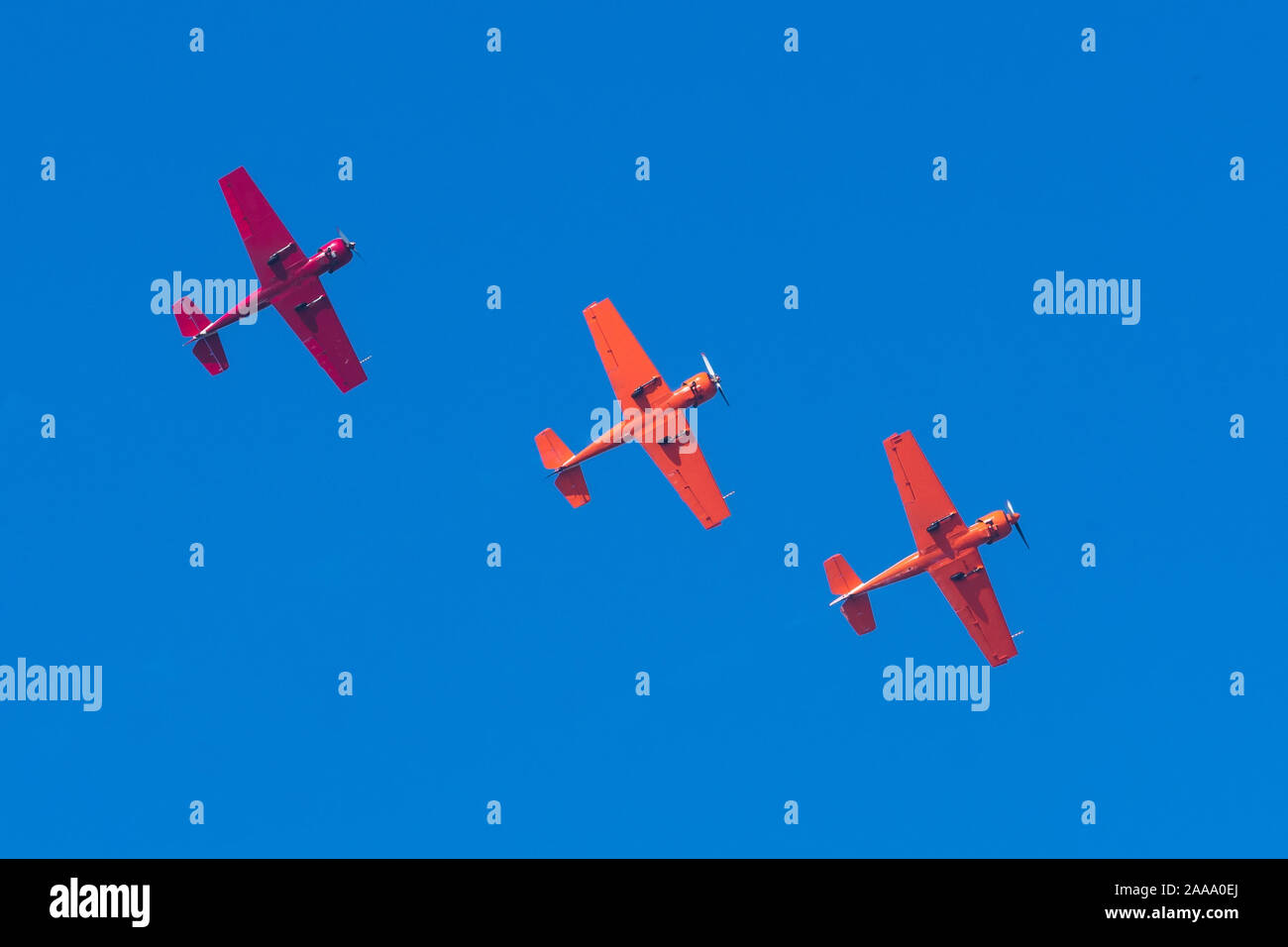 Three light-engine turboprop red aircraft fly in formation in a ...