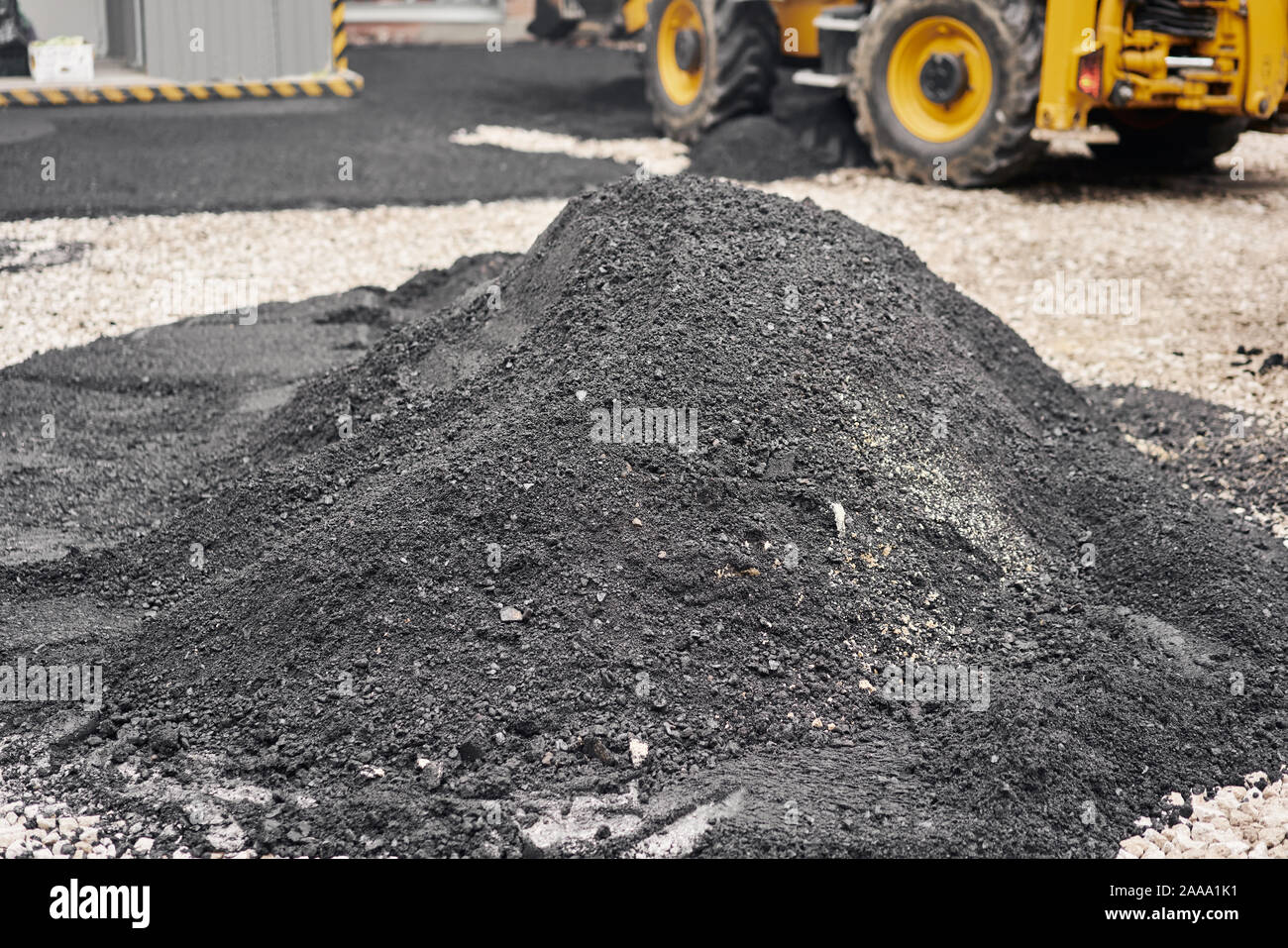 Heap new hot asphalt. Laying asphalt, covering the pit, on the rubble ...