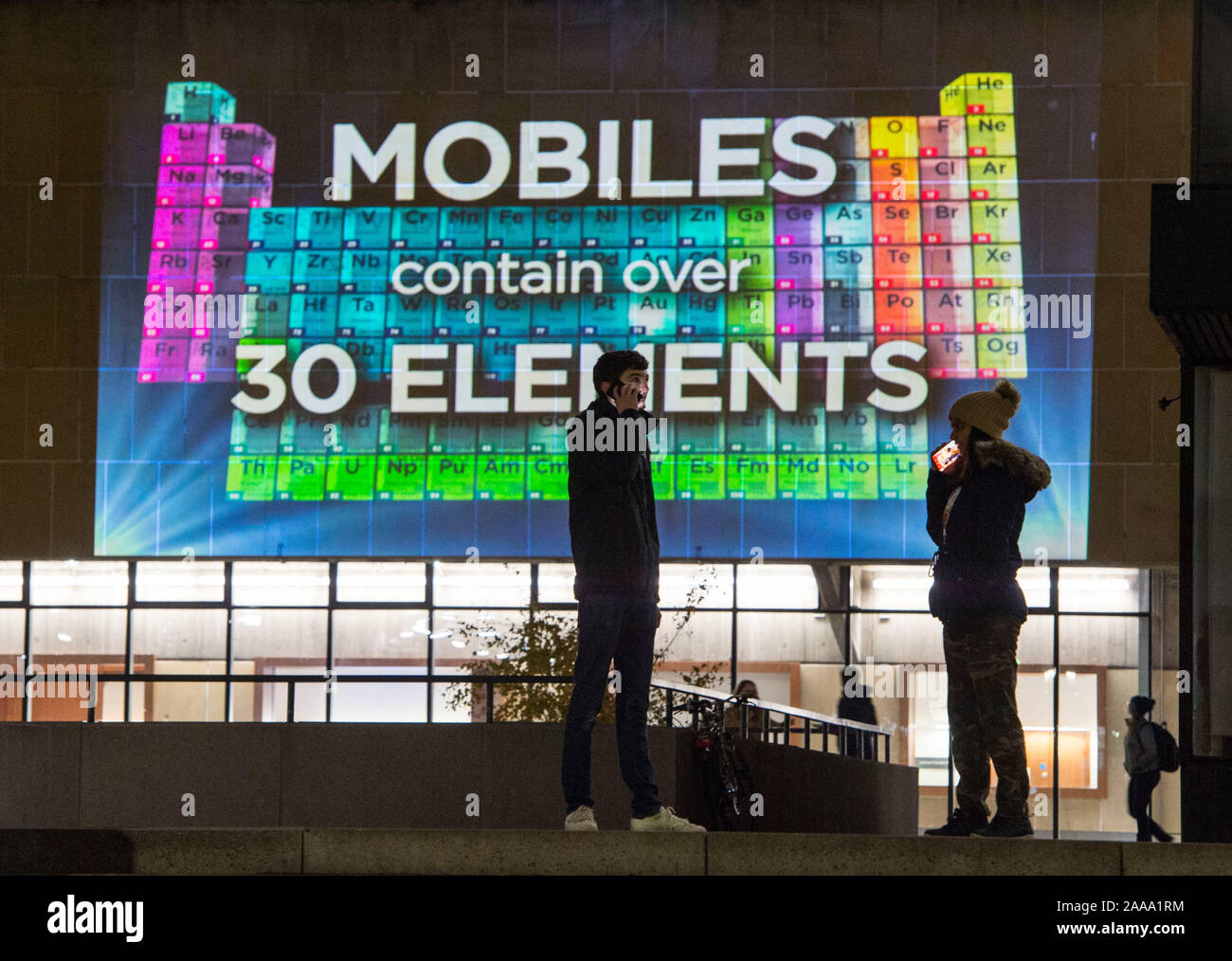 Students on their mobile phones with a backdrop of a light display at ...