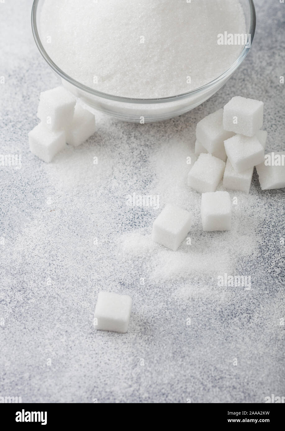 Glass bowl of natural white refined sugar with cubes on light table ...