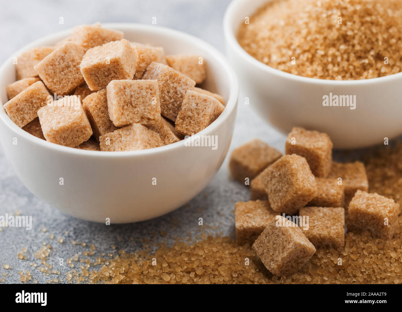 White bowl plates of natural brown sugar cubes and refined sugar on ...
