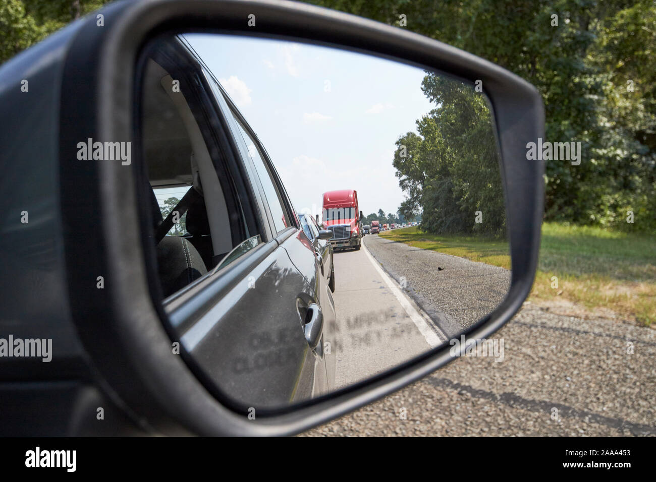 looking in side view mirror of traffic backed up driving along ...