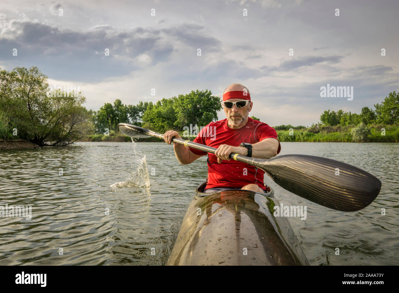 senior male paddler is paddling a long, narrow and fast racing sea ...