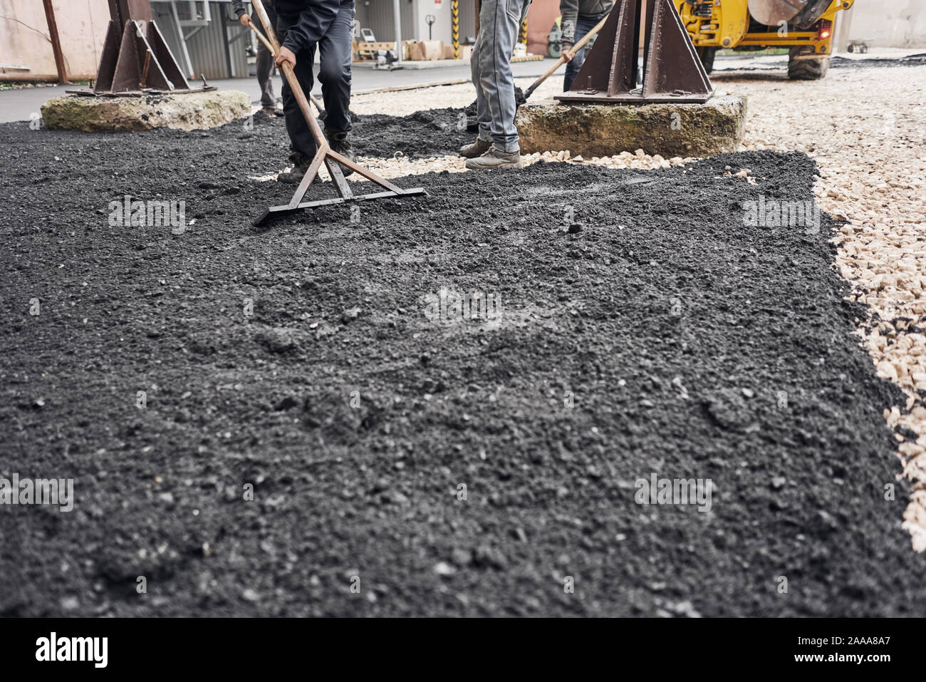 Laying new asphalt, covering the pit, on the rubble. Workers carry in ...