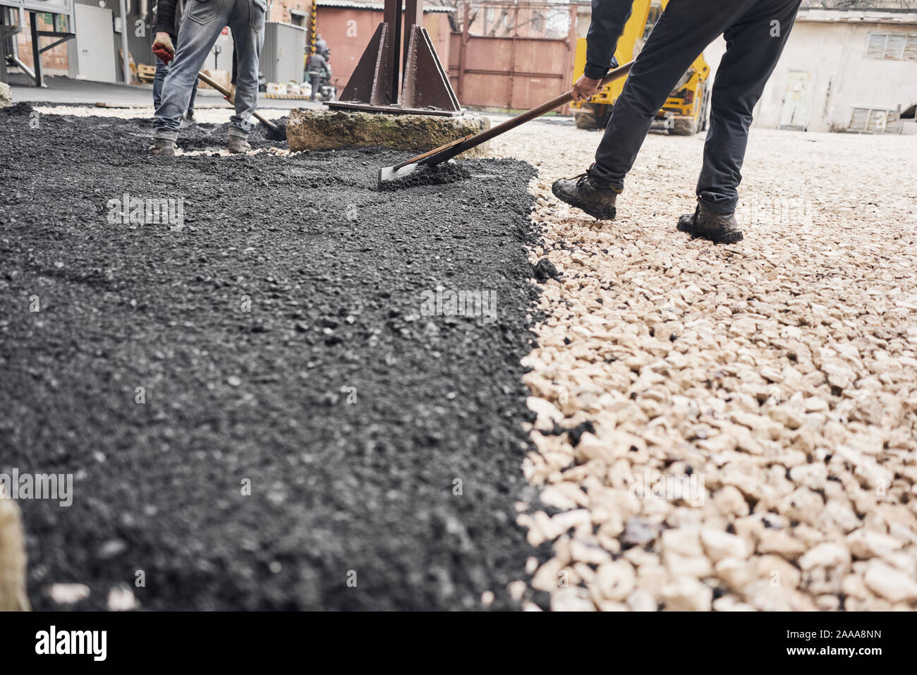 Laying new asphalt, covering the pit, on the rubble. Workers carry in ...