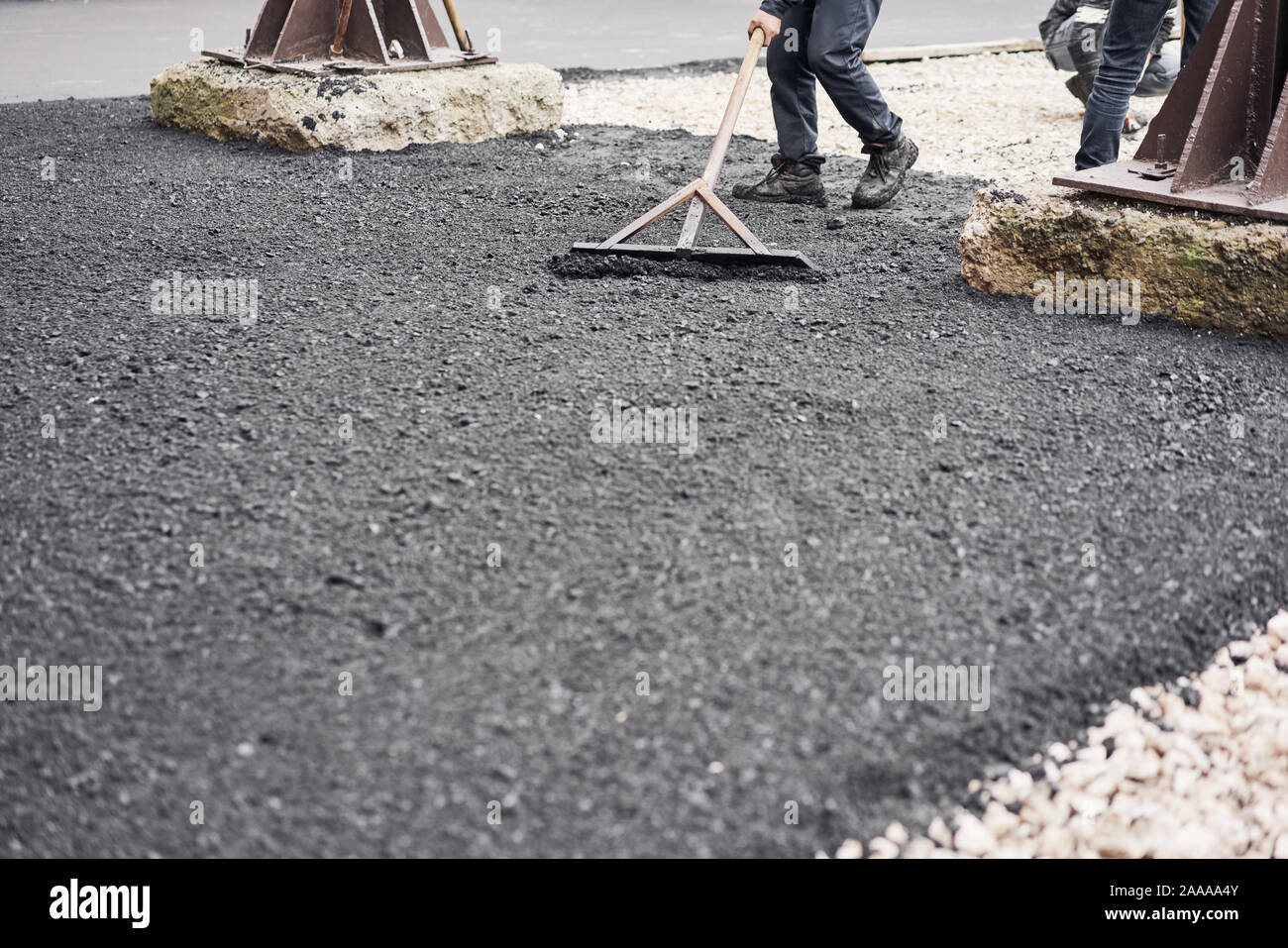 Laying new asphalt, covering the pit, on the rubble. Workers carry in ...