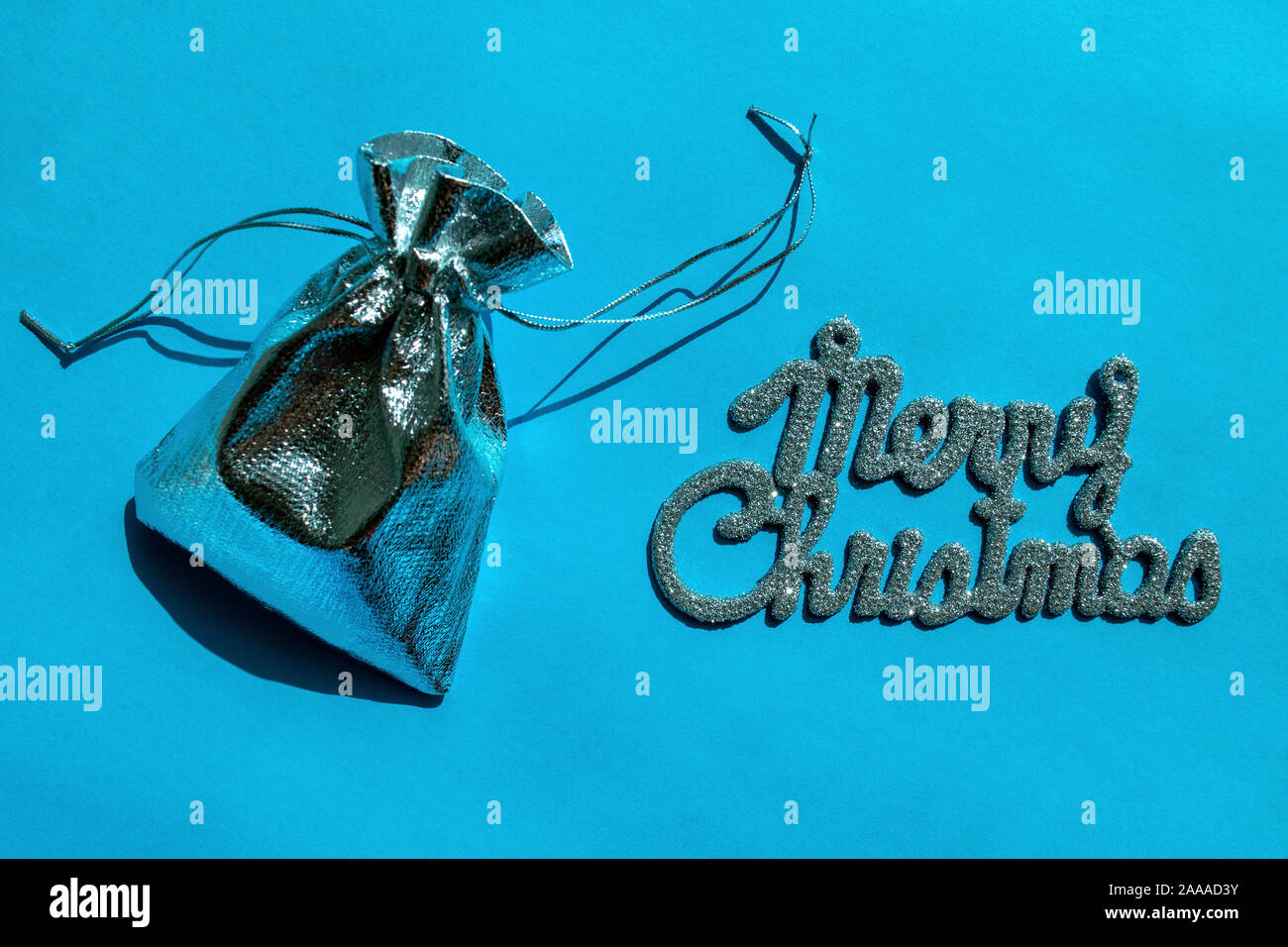 Merry Christmas title and silver present box on blue background. Silver ...