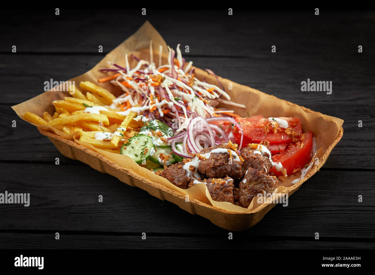 Cardboard box filled with barbecue food: skewers, vegetables, baked ...
