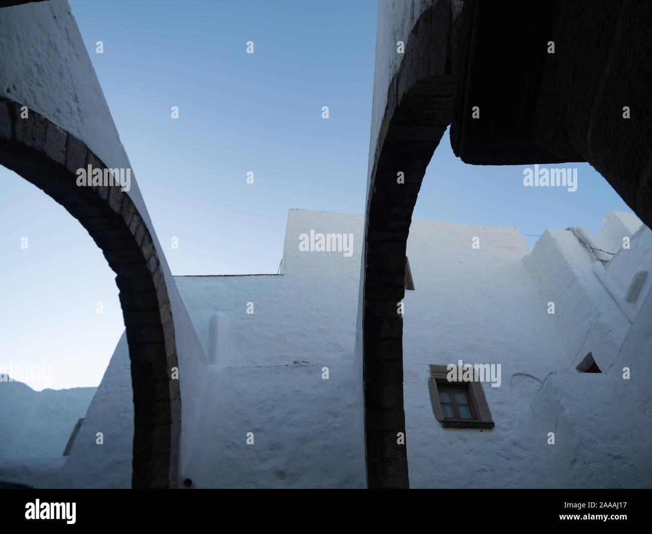 Two gray stone archways with the white stucco walls of buildings of the ...