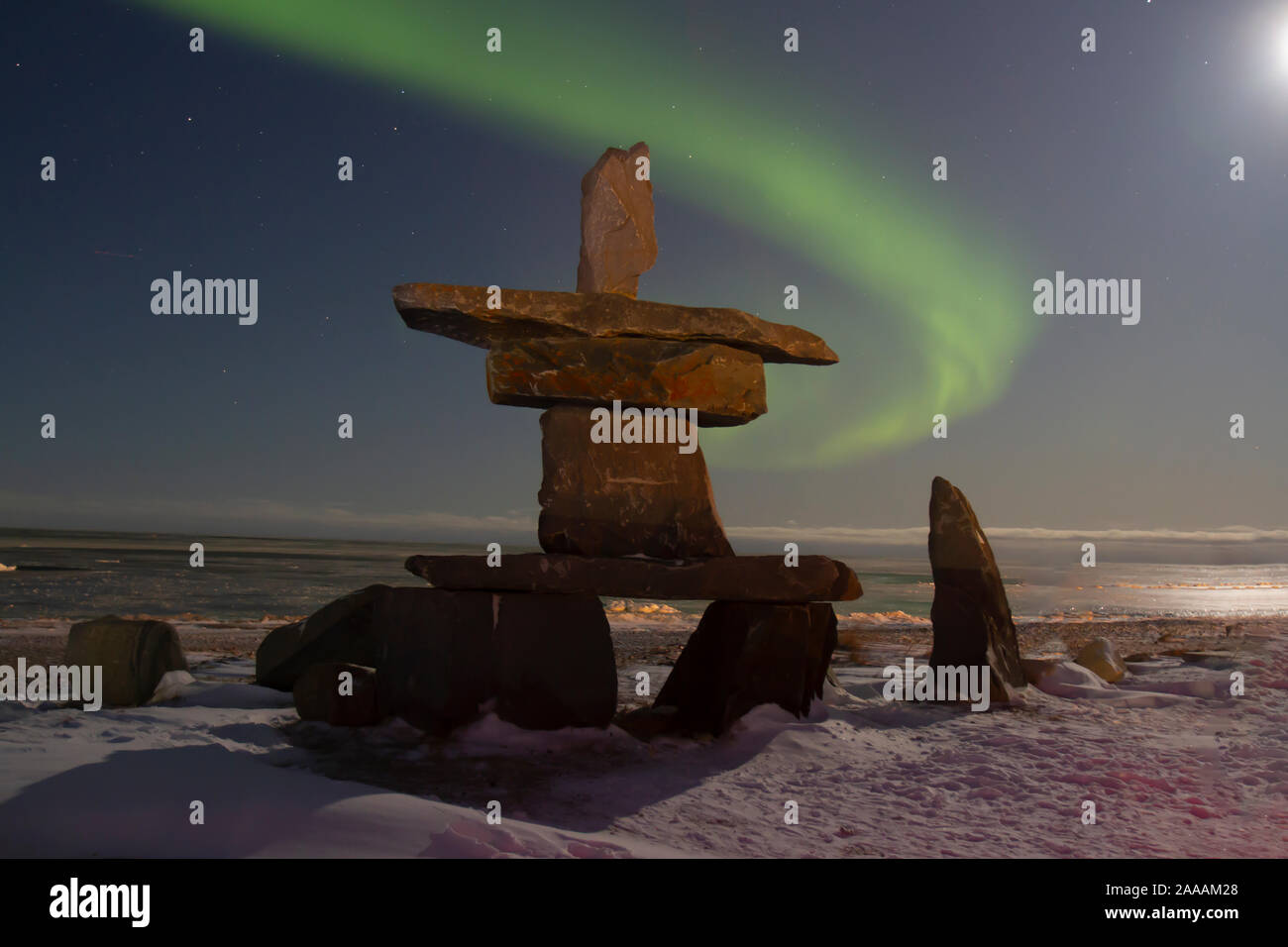 Northern lights over native inukshuk rock tower on banks of Hudson Bay ...
