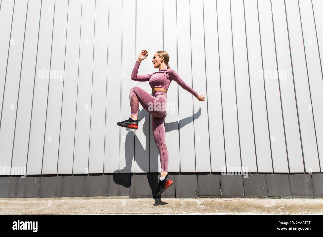 Fit young woman doing cardio interval training against grey background ...