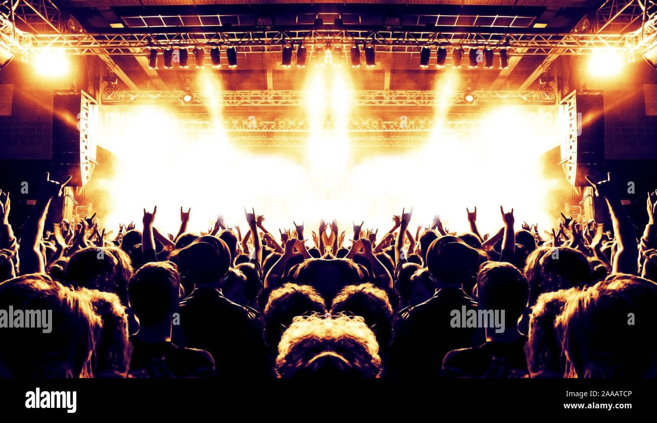 A shot taken in front of a concert stage lit in the night, people are ...