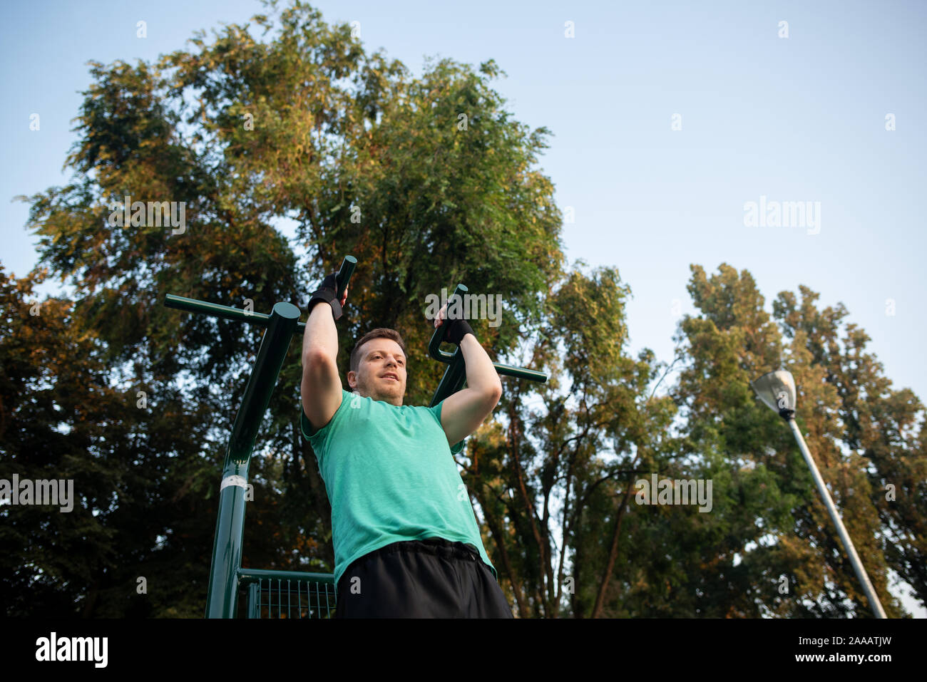 Guy training in outdoor gym on exercise equipment Stock Photo - Alamy