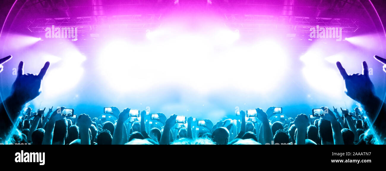 A shot taken in front of a concert stage lit in the night, people are ...