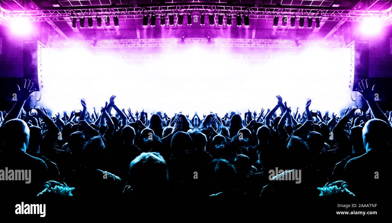 A shot taken in front of a concert stage lit in the night, people are ...