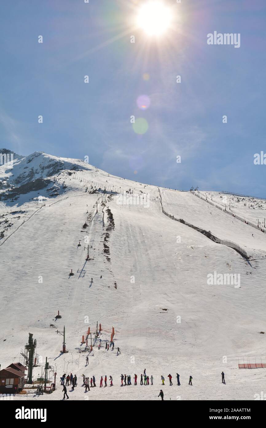People skiing at a ski resort with mountains full of snow Stock Photo ...