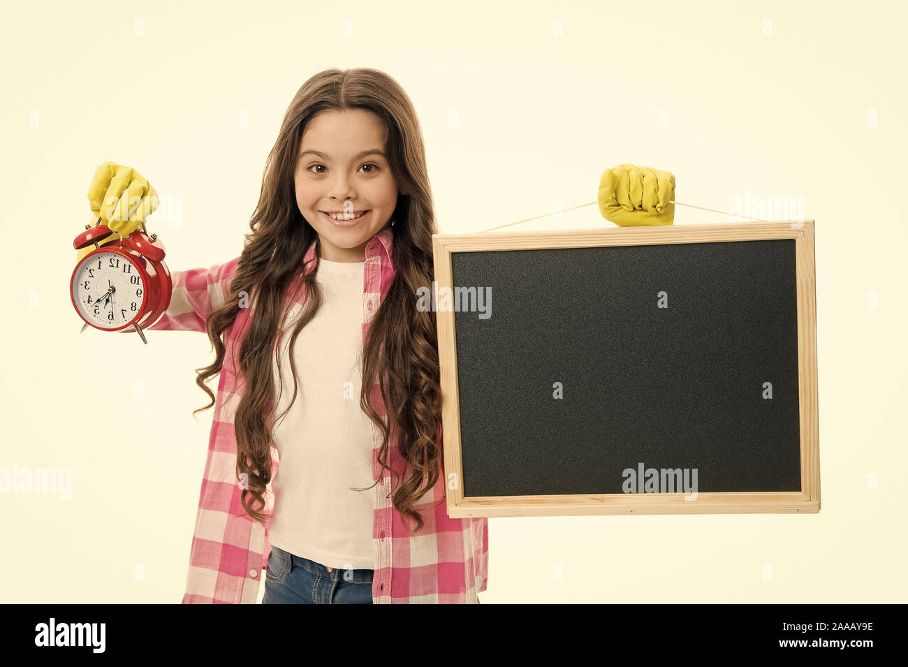 Its class time. Happy little girl holding blank blackboard and alarm ...