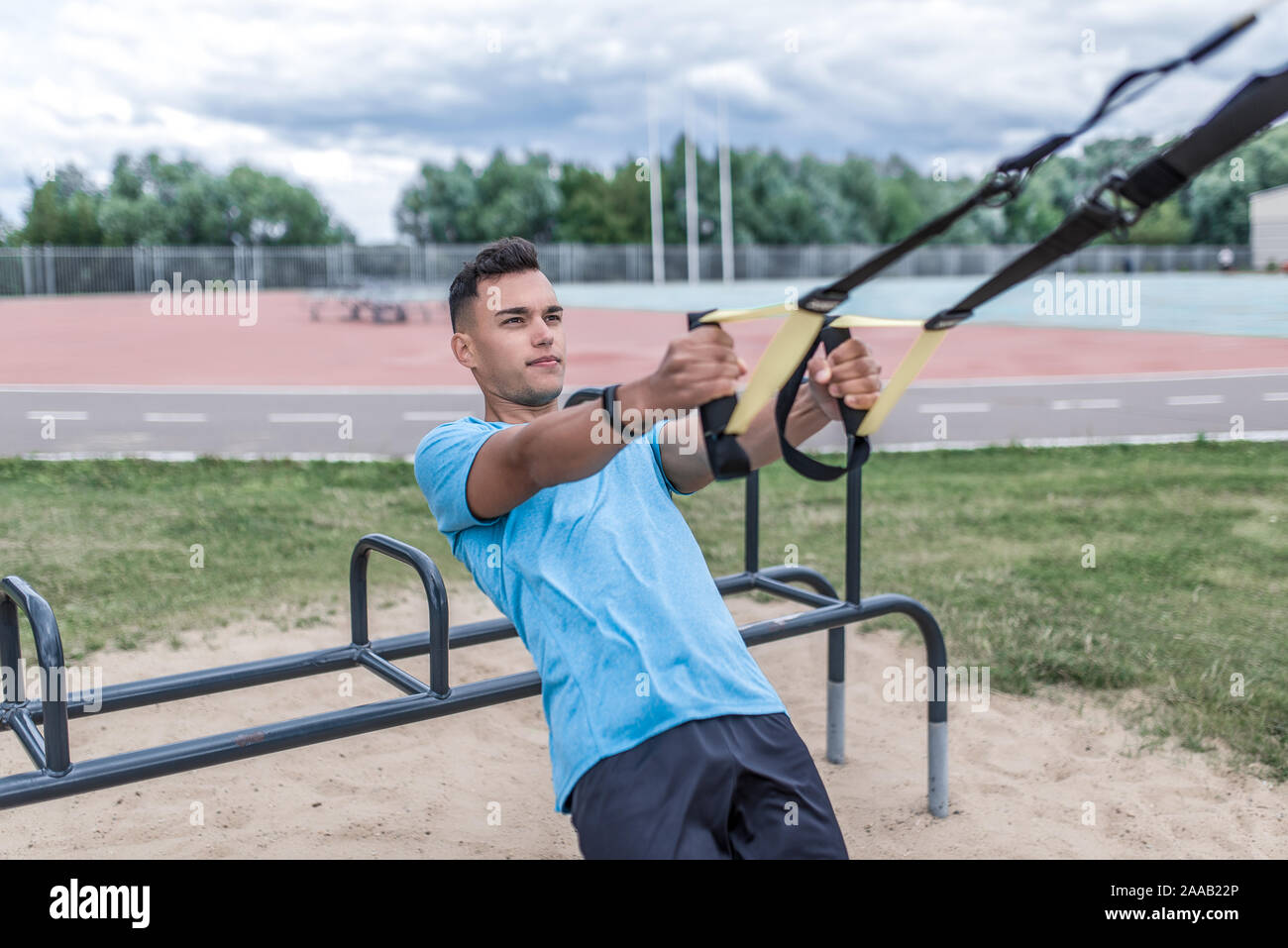 Young sportsman, male athlete, pulls himself on hinges, straps for ...