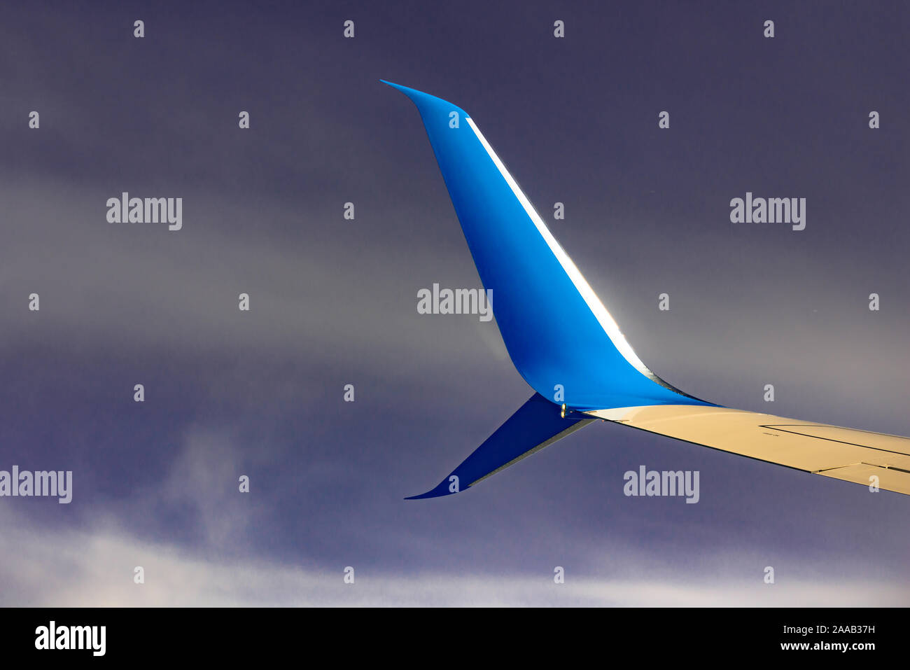 Airplane wing. Blue wing tip of the aircraft against the blue sky with ...