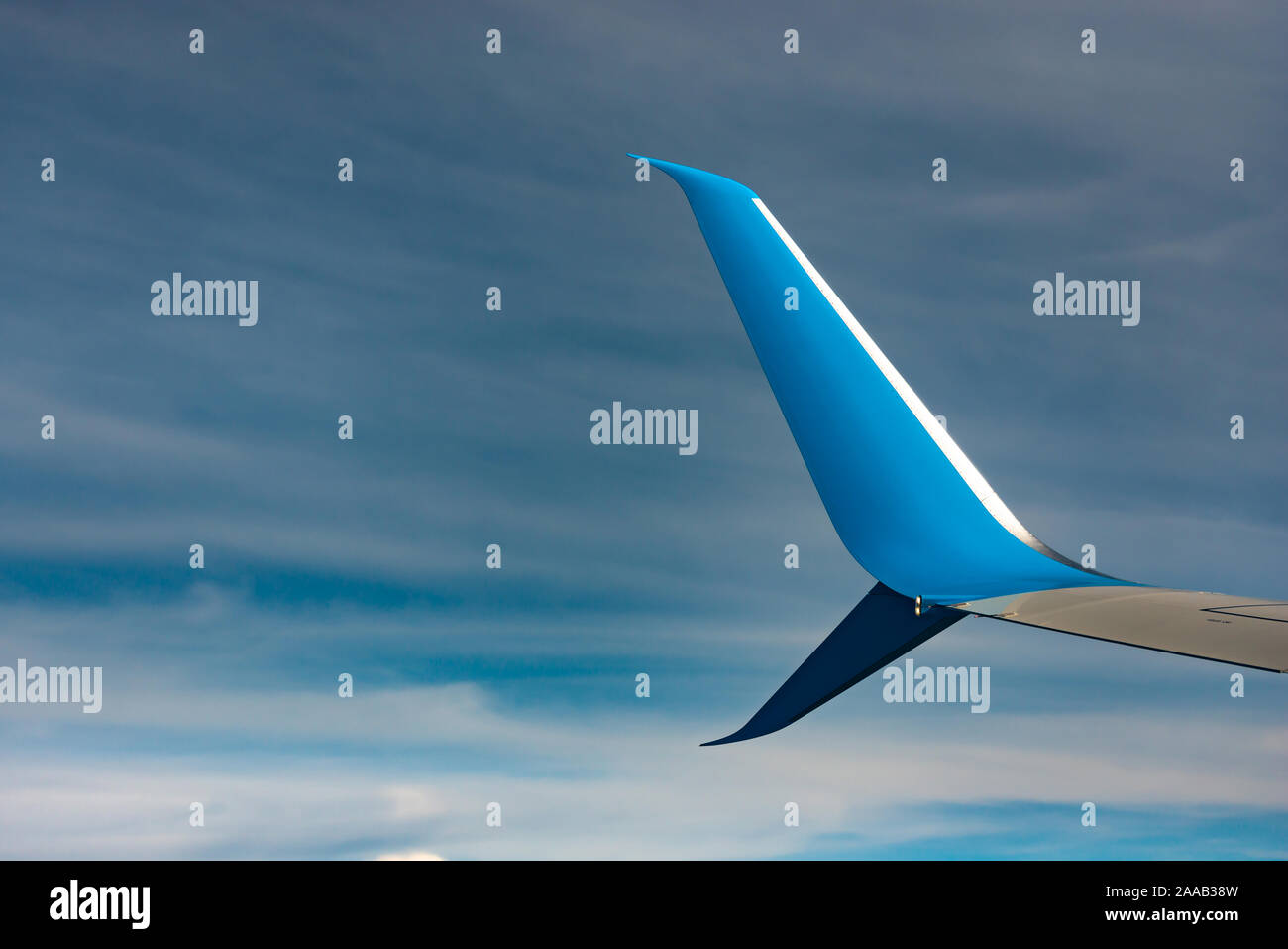 Airplane wing. Blue wing tip of the aircraft against the blue sky with ...