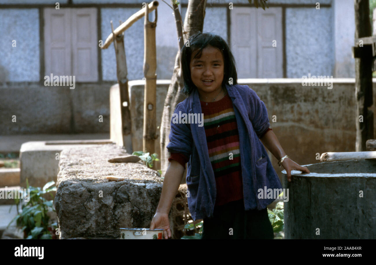 A young, indigenous Palaung girl collects water from the well in her ...