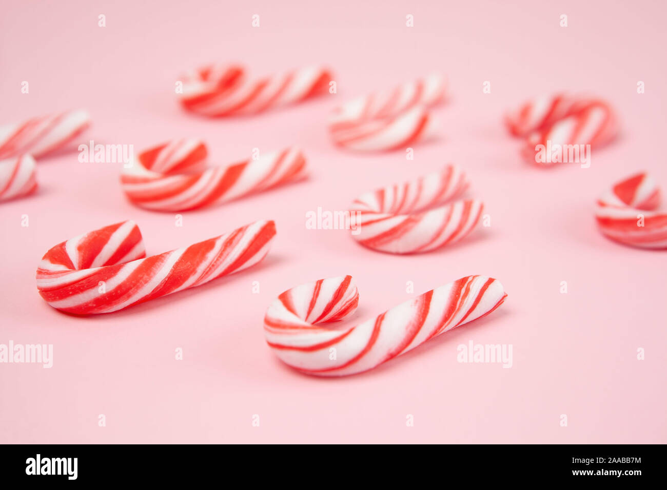 Striped peppermint sticks on pink background in perspective with ...
