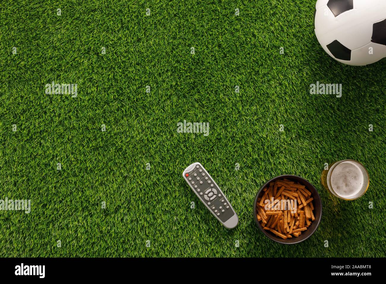 Soccer ball on a green field and ottoman for a fan with snacks and a TV ...