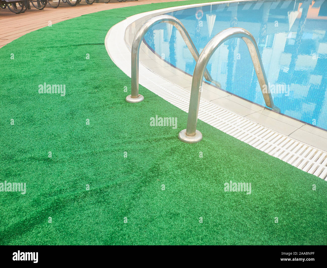 Grab bars ladder of swimming pool and green carpet Stock Photo - Alamy